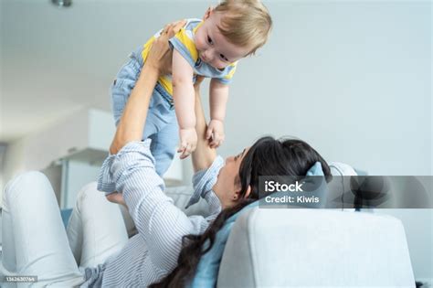 백인 을 사랑하는 엄마는 거실에서 소파에 아기 소년 아이와 함께 재생합니다 행복한 가족 매력적인 아름다운 돌보는 젊은 어머니 리프팅 유아 아들 집에서 아침에 비행기 게임을