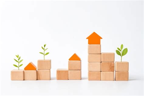Wooden Blocks With Green Plants And Orange House Shapes On Top Representing Growth And Success