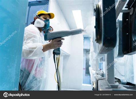 Powder Coating Of Metal Parts A Woman In A Protective Suit Sprays White Powder Paint From A Gun