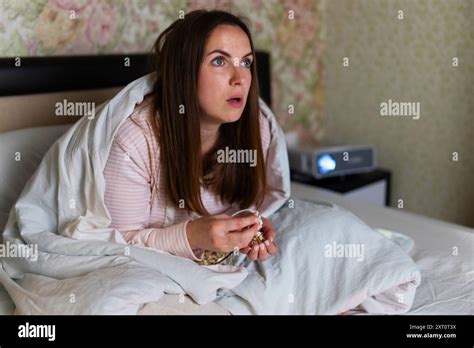 Woman Wrapped In Blanket Watching TV In Bed Stock Photo Alamy