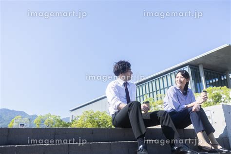階段に座る男女の写真素材 127123718 イメージマート