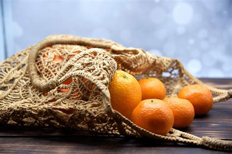 밝은 오렌지와 귤은 친환경 소재로 만든 재사용 가능한 식료품 백에 넣습니다 흐릿한 배경에 거친 나무 테이블에 0명에 대한 스톡