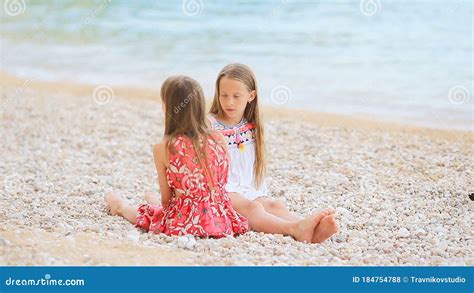 Two Little Happy Girls Have A Lot Of Fun At Tropical Beach Playing