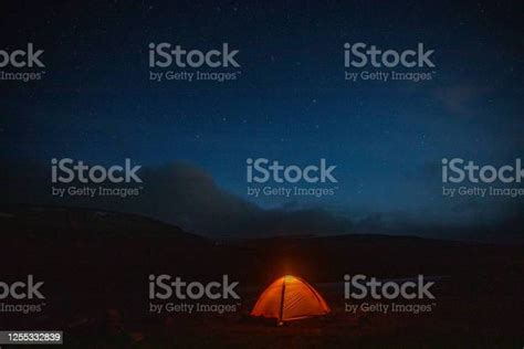 야외 레크리에이션의 개념 극적인 저녁 하늘 아래 산에서 빛나는 주황색 텐트 붉은 일몰과 배경에 산 여름 풍경 밤 하루 시간대에