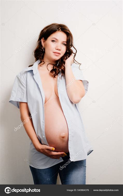 Attractive Pregnant Woman In Jeans And A Shirt On A Naked Body Womens Health Stock Photo