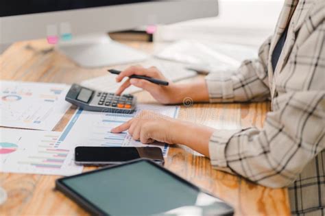 Businessperson Calculating Budget With Calculator And Analyzing Financial Charts And Graphs On