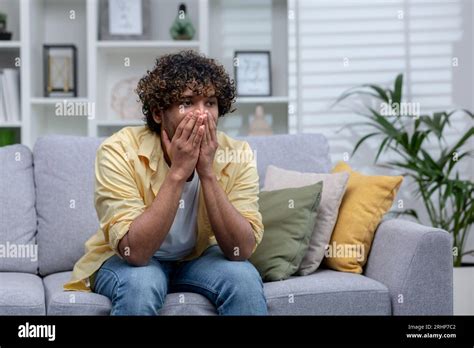 Sad Depressed Man Sitting Alone At Home On Sofa In Living Room