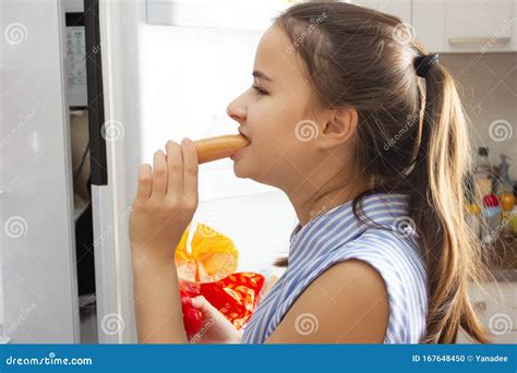 A Garota Olha Na Geladeira Faminta Come Salsicha Foto De Stock