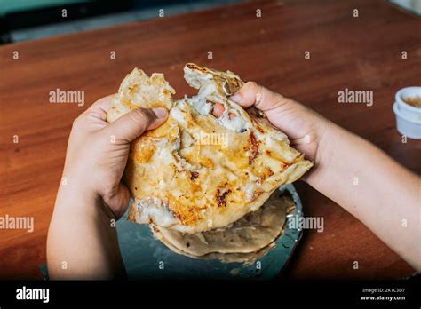 View Of Hands Dividing Delicious Salvadoran Pupusas On Wooden Table