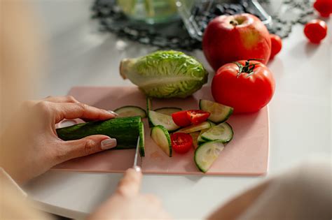 하얀 테이블에 칼로 신선한 익은 야채를 자르고 건강한 식사를 준비하는 여성의 손 부엌에서 요리하는 과정의 클로즈업 사진 유기농