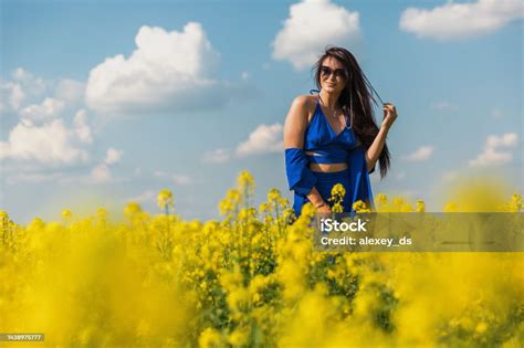 紺色のスーツとサングラスをかけた女性が黄色い草原の花でいっぱいの野原の真ん中に立っている 1人のストックフォトや画像を多数ご用意 1人