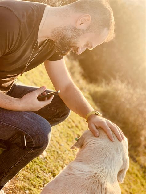 갈색 티셔츠와 파란색 데님 청바지를 입은 여자가 흰색 옆의 갈색 잔디밭에 앉아 있습니다 사진 Unsplash의 무료 개 이미지