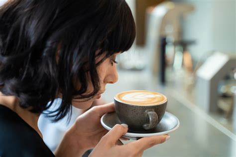 라떼 아트 커피 한 잔을 들고 실내 카페 레스토랑에서 아름다운 여성 백인 고객 여자는 커피를 보고 행복과 미소로 향기로운 냄새를 맡는다 음료 마시는 개념 여자에 대한 스톡