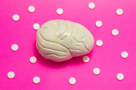 뇌의 3d 해부학 모델은 장식 물방울 무늬로 흰색 알약으로 둘러싸인 분홍색 배경에 있습니다 뇌 및 신경질환 약리치료의 약리학적 정제 치료에 의한 의학 개념 0명에 대한 스톡