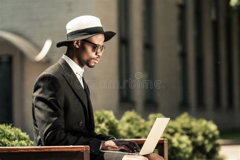 Stylish Man Wearing Suit Working On Laptop While Sitting Stock Image