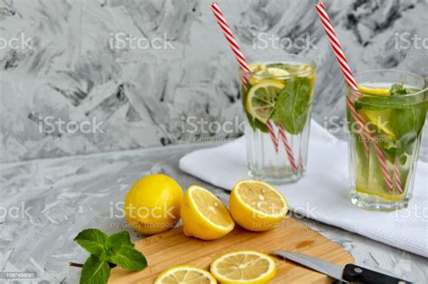 레모네이드를 만드는 과정 나무 판에는 칼 옆에 레몬과 민트가 있습니다 배경에는 레모네이드 안경이 있습니다 여름 음료 레몬과 민트