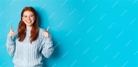 Premium Photo Cheerful Teen Girl With Red Hair Pointing Fingers At