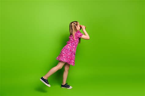 빨간 장난감을 들고 눈에 띄는 역동적인 포즈를 취하면서 단단한 녹색 배경에서 장난기 넘치는 순간을 즐기는 사랑스러운 어린 소녀 8 9 살에 대한 스톡 사진 및 기타 이미지