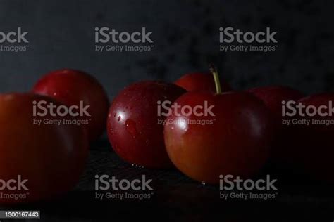 검은 색 배경에 물방울이 있는 바구니에 신선한 붉은 육즙이 많은 자두를 클로즈업합니다 사츠마 빨간 자두의 클로즈업 샷 검정색