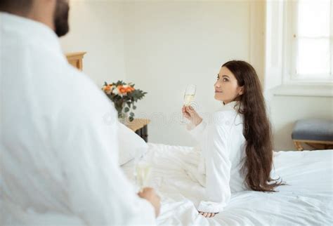 Couple Drinking Sparkling Wine Holding Glasses Sitting In Hotel Room