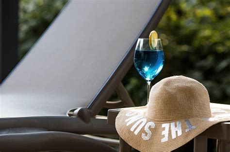 맛있는 블루 칵테일 블루 라군한 잔과 긴 의자 배경에 노란 레몬 과즙이 풍부한 과일 블루와 큐라소 리큐어 얼음 조각 레몬 한 조각을 곁들인 알코올 칵테일 0명에 대한 스톡