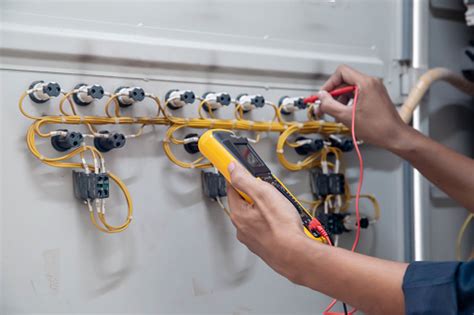 Engineer Testing Electrical System Using A Multimeter To Measure The Current At The Control