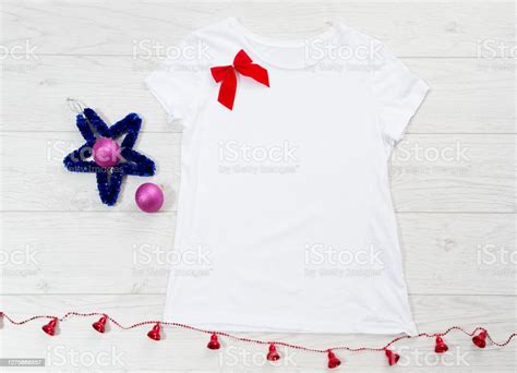 복사 공간과 크리스마스 휴일 개념흰색 빈 템플릿 티셔츠를 닫습니다 흰색 나무 배경에 상단 보기 모형 티셔츠와 빨간색 활 새해 복 많은 장식 액세서리 Xmas 의상 T 셔츠에