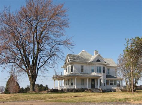 A Large White House Sitting On Top Of A Lush Green Field