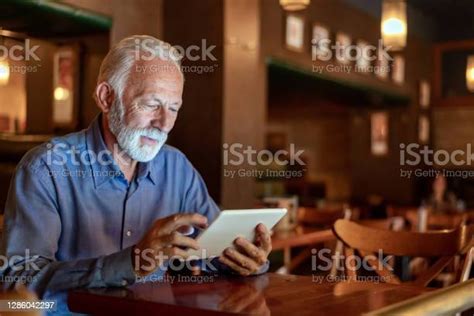 커피숍에서 커피 한 잔을 들고 디지털 태블릿을 바라보는 사업가 카페에서 디지털 태블릿을 작업하는 사업가 65 69세에 대한 스톡