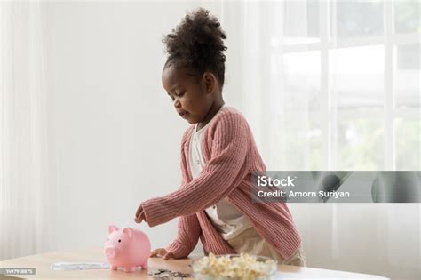 돼지 저금통에 돈을 넣는 소녀 아이 돼지 저금통에 동전을 삽입하는 아프리카 계 미국인 소녀 아이 미래 개념을위한 어린이 투자 2