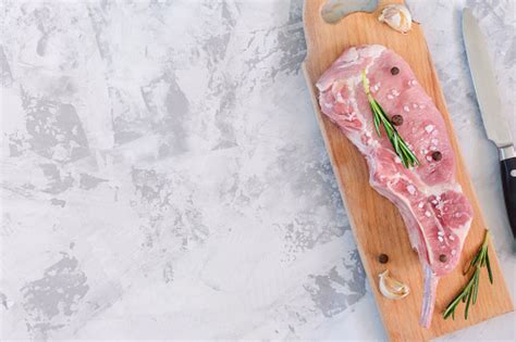 생고기의 조각이 커팅 보드에 놓여 있습니다 후추와 로즈마리가 있는 돼지고기 스테이크 회색 돌 배경에 공간을 복사 합니다 텍스트에 대 한 장소 사진 0명에 대한 스톡 사진 및