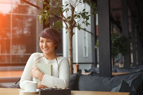 Premium Photo Happy Girl Embracing Book In Cafe
