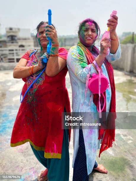 두 명의 이미지 힌두교 인도 여성은 물 권총을 들고 페인트 분말 컬러 Gulal 울렸다에 덮여 서서 색상의 홀리 축제에서 장난과 사랑 페인트와 물 싸움 카메라를보고 2명에