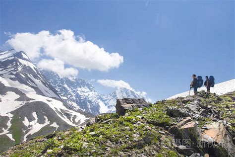 高山风景与两位徒步旅行者在高山山顶看雪山在晴朗的夏日。登山者徒步攀登。格鲁吉亚上斯瓦涅季亚地区的休闲活动。远足运动照片 正版商用图片