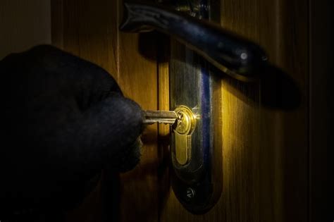 Premium Photo The Thief Tries To Open The Lock In The Door With A