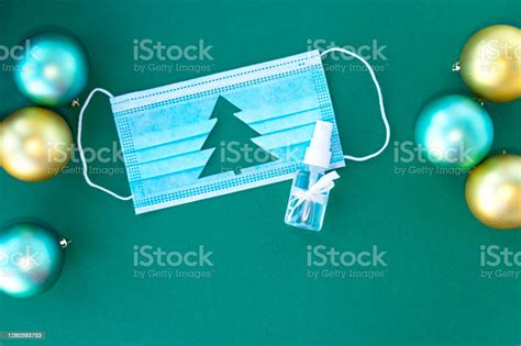 녹색 배경에 크리스마스 트리의 컷 아웃 실루엣과 흰색 활과 의료 보호 마스크와 소독제 마스크 근처 크리스마스 공 크리스마스 또는