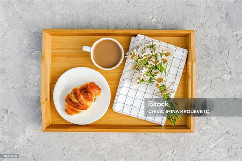 회색 석재 테이블에 나무 트레이에 우유 갓 구운 크루아상 체크 무늬 냅킨과 카모마일 꽃커피 한 잔 컨셉 굿모닝 탑 뷰 아침