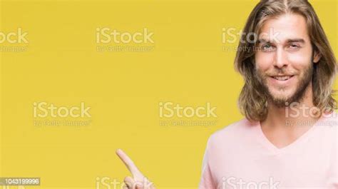 웃 고 옆에 두 손과 손가락으로 가리키는 카메라 보고 격리 된 배경 위에 긴 머리를 가진 젊은 잘생긴 남자 가리키기에 대한 스톡