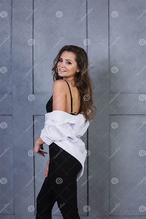 Portrait Of A Young Smiling Woman On A Gray Wall Background A Beautiful Girl In White Shirt And