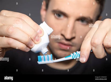 Empty Tube Of Toothpaste With Man In Background Squeezing The Container