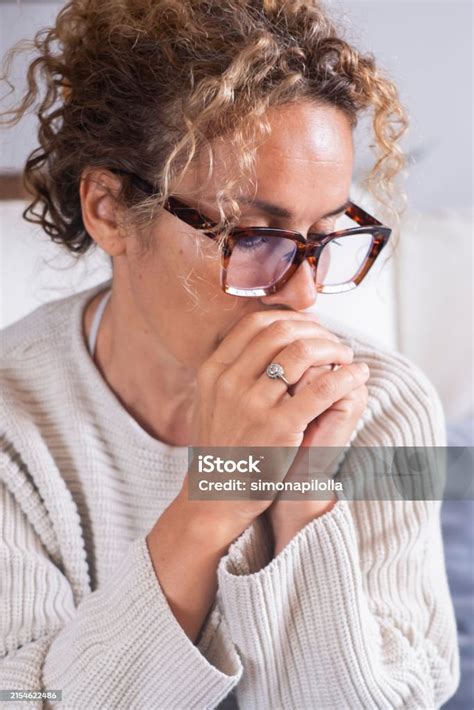 집에서 혼자 소파에 앉아 슬픈 표정으로 아래를 내려다보고 있는 사려 깊은 여자 문제와 우울증이 있는 사람들 중년 여성의 생활