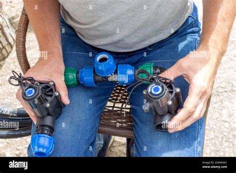 A Man Assembles A Drip Irrigation System By Assembling Pipeline Components And Automatic Valves