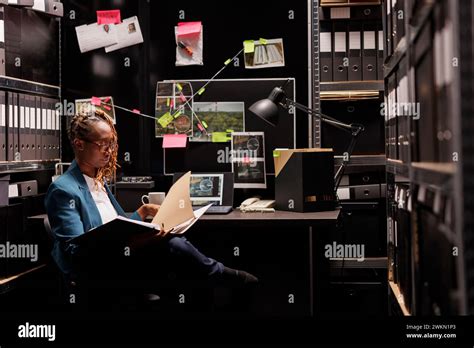 Criminal Justice Professional Reading Crime Case File In Police Detective Office Room African