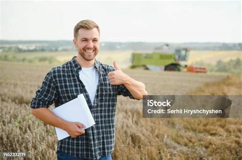 밭에서 수확하는 동안 콤바인 수확기 앞에 태블릿을 들고 있는 잘생긴 농부 계절에 대한 스톡 사진 및 기타 이미지 계절 곡물 수확량 곡초류 Istock