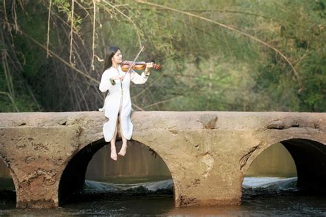 Premium Photo Woman Playing Violin While Sitting On Bridge Over River