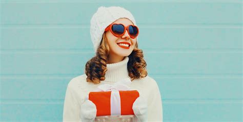 흰색 니트 모자 파란색 배경에 스웨터를 입고 그녀의 손에 빨간 선물 상자를 들고 행복한 미소 여자의 겨울 초상화 25 29세에 대한 스톡 사진 및 기타 이미지 Istock