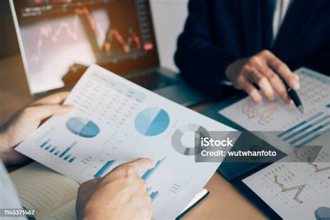 두 투자자가 종이에 있는 주식 데이터 그래프를 분석 하 고 랩톱 화면에서 데이터를 보는 것과 함께 일하고 있습니다 가리키기에 대한 스톡 사진 및 기타 이미지 Istock