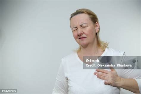 의 성인 여자 심장이 아파요 그녀는 가슴에 손을 댔다 그녀는 피곤하다 교정 입과 닫힌 눈 텍스트를위한 공간 피곤한 질병 가벼운 옷 금발 머리 흰색 배경 도색되지 않은 머리