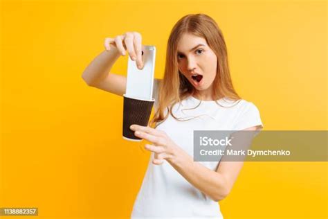 분노와 함께 자극 소녀 노란색 배경에 커피 한 잔으로 전화를 내려 T 셔츠에 대한 스톡 사진 및 기타 이미지 T 셔츠 노랑