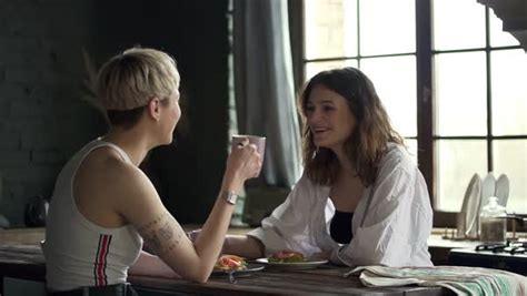 Young Lesbian Couple Is Eating And Talking While Sitting At Table In